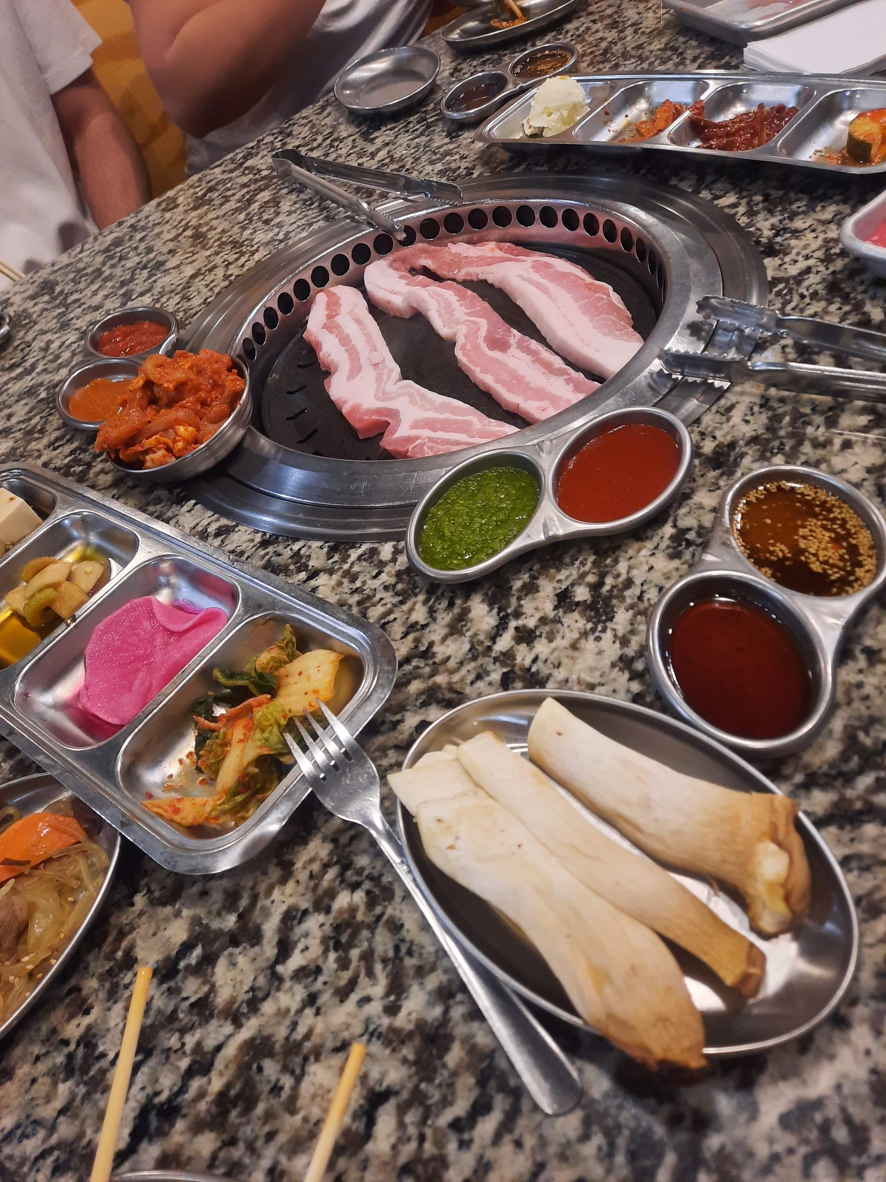 Korean bbq restaurant grill surrounded by raw food